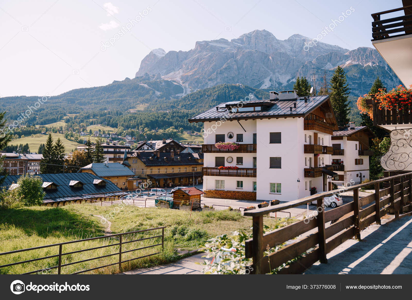 White houses and rocky mountains with dense green forest in Dolomites ...