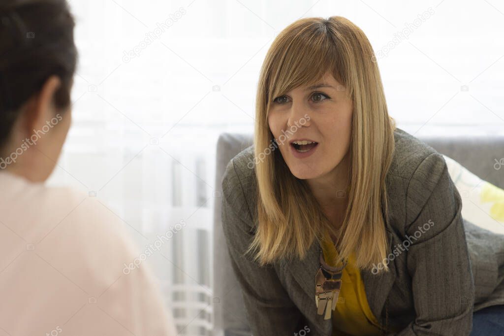 Dos mujeres teniendo una conversación informal sentadas en un sofá en ...