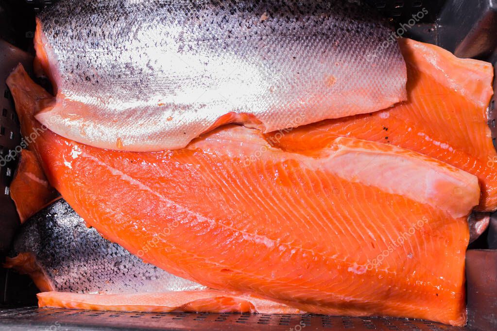 Trozos de pescado rojo con la piel fría, acostado en un recipiente ...