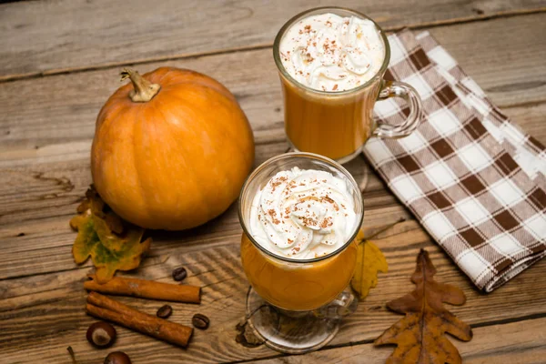 Pumpkin smoothie, spice latte with whipped cream on the rustic wooden background. selective ...