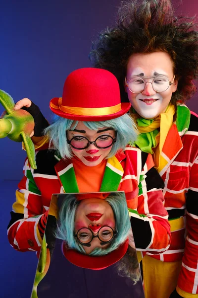 Two clowns a man and a woman with bright makeup in colored costumes say ...