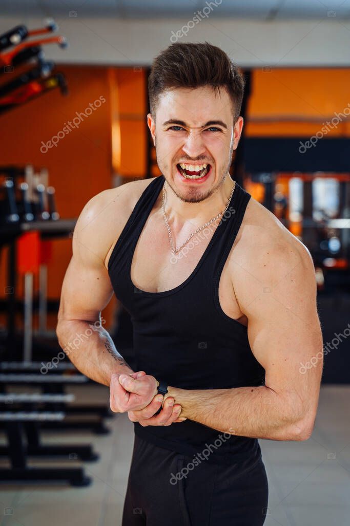 Joven musculoso gritando y mostrando su bíceps con la cara enojada en ...