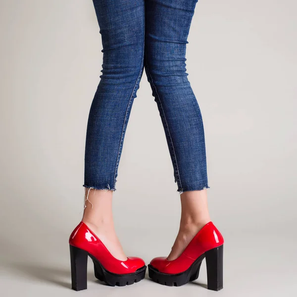 Woman in jeans black high heel shoes with a padlock posing on a gray ...