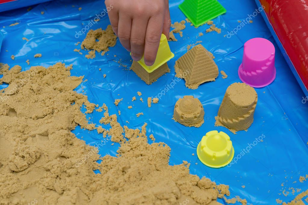 niño haciendo diferentes formas por arena con moldes 2023