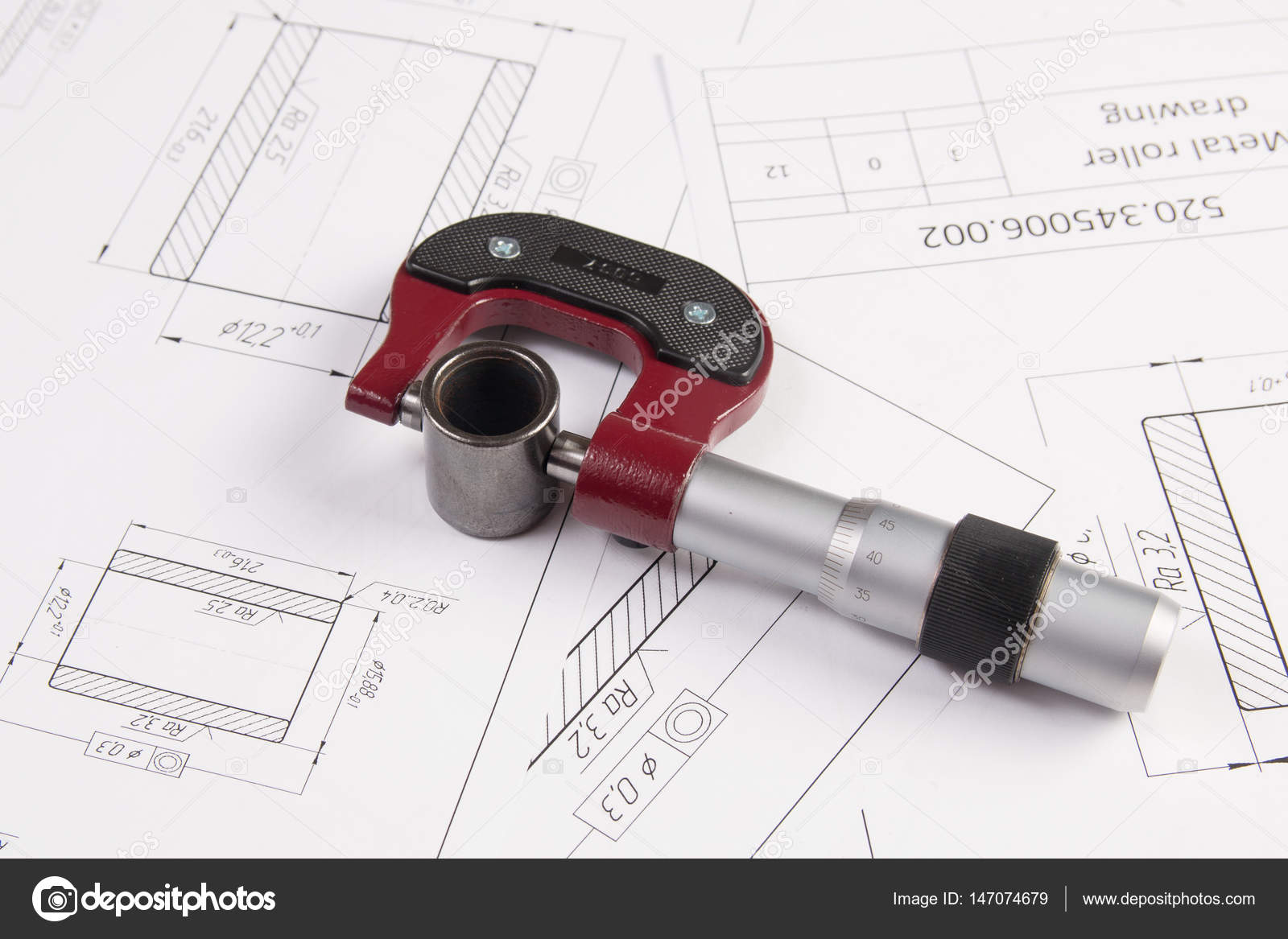Metal cylinders, micrometer and calipers on printed engineering ...