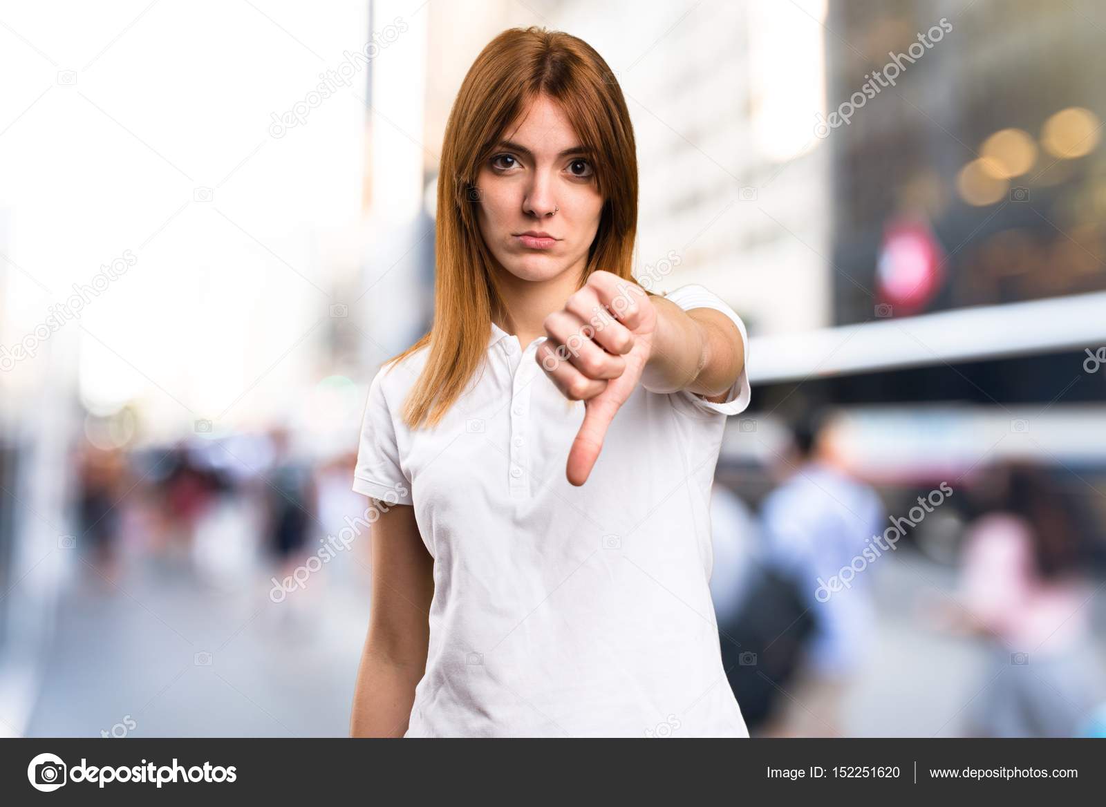 Beautiful young girl making bad signal on unfocused background — Stock ...