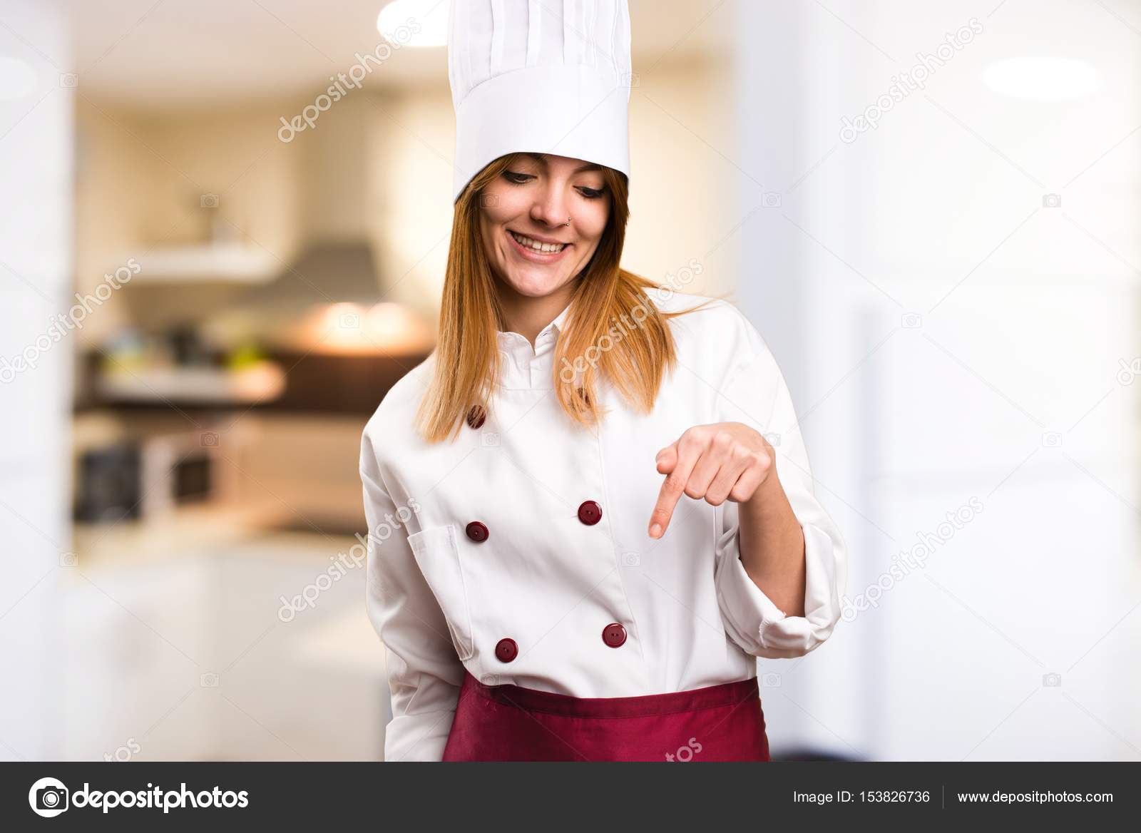Beautiful chef woman pointing down in the kitchen — Stock Photo ...
