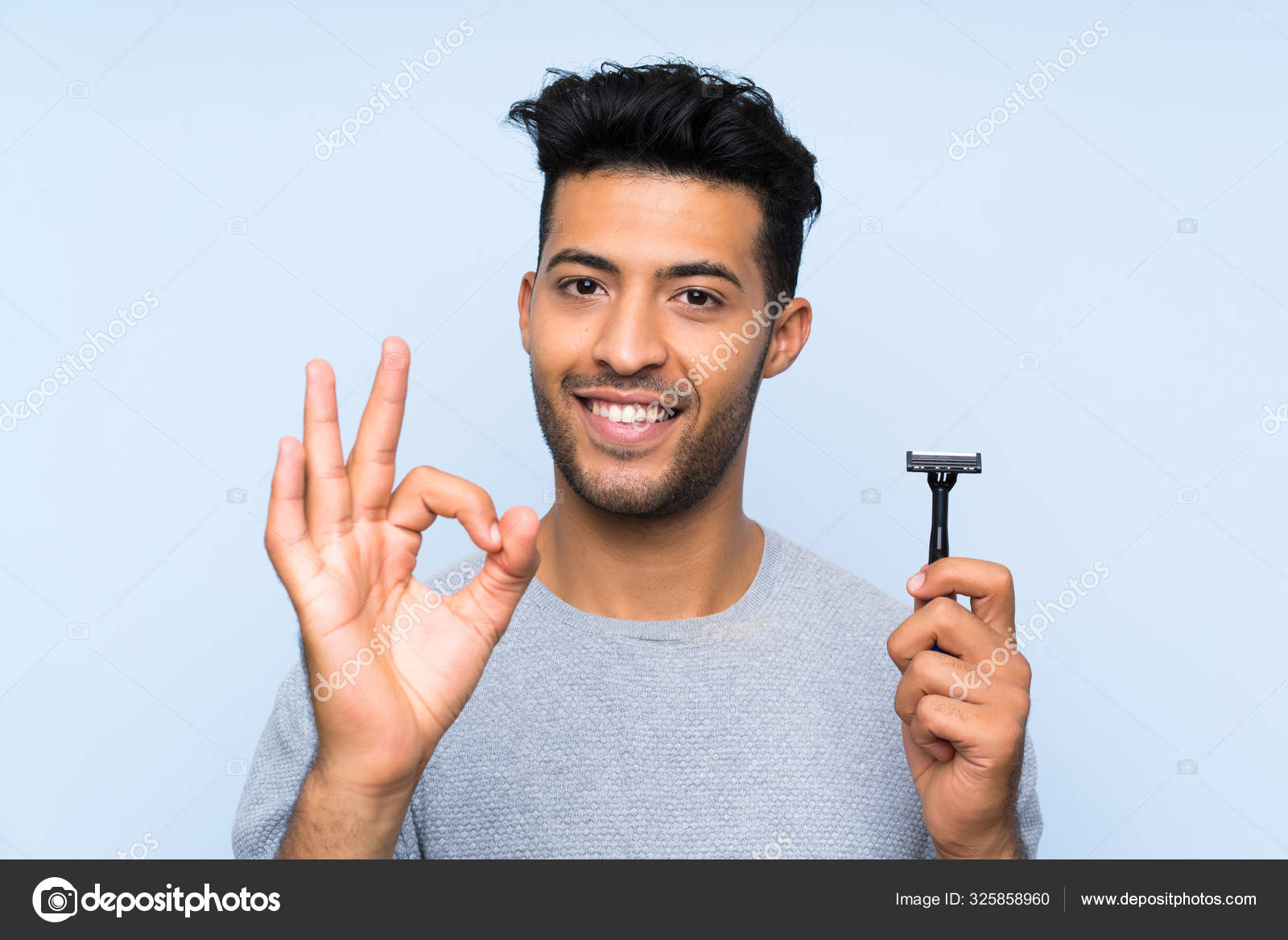 Young Man Shaving His Beard Isolated Blue Background Showing Sign Stock