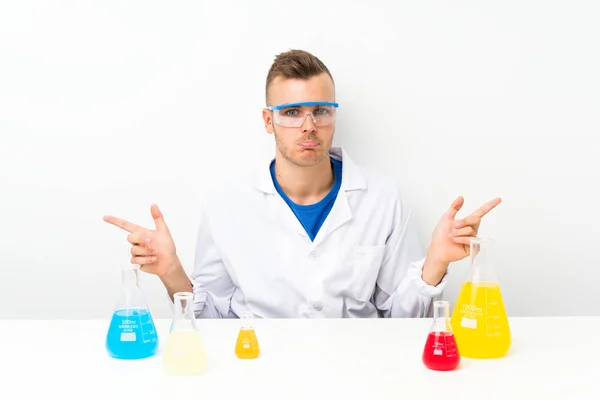 Young scientific with lots of laboratory flask pointing to the laterals ...