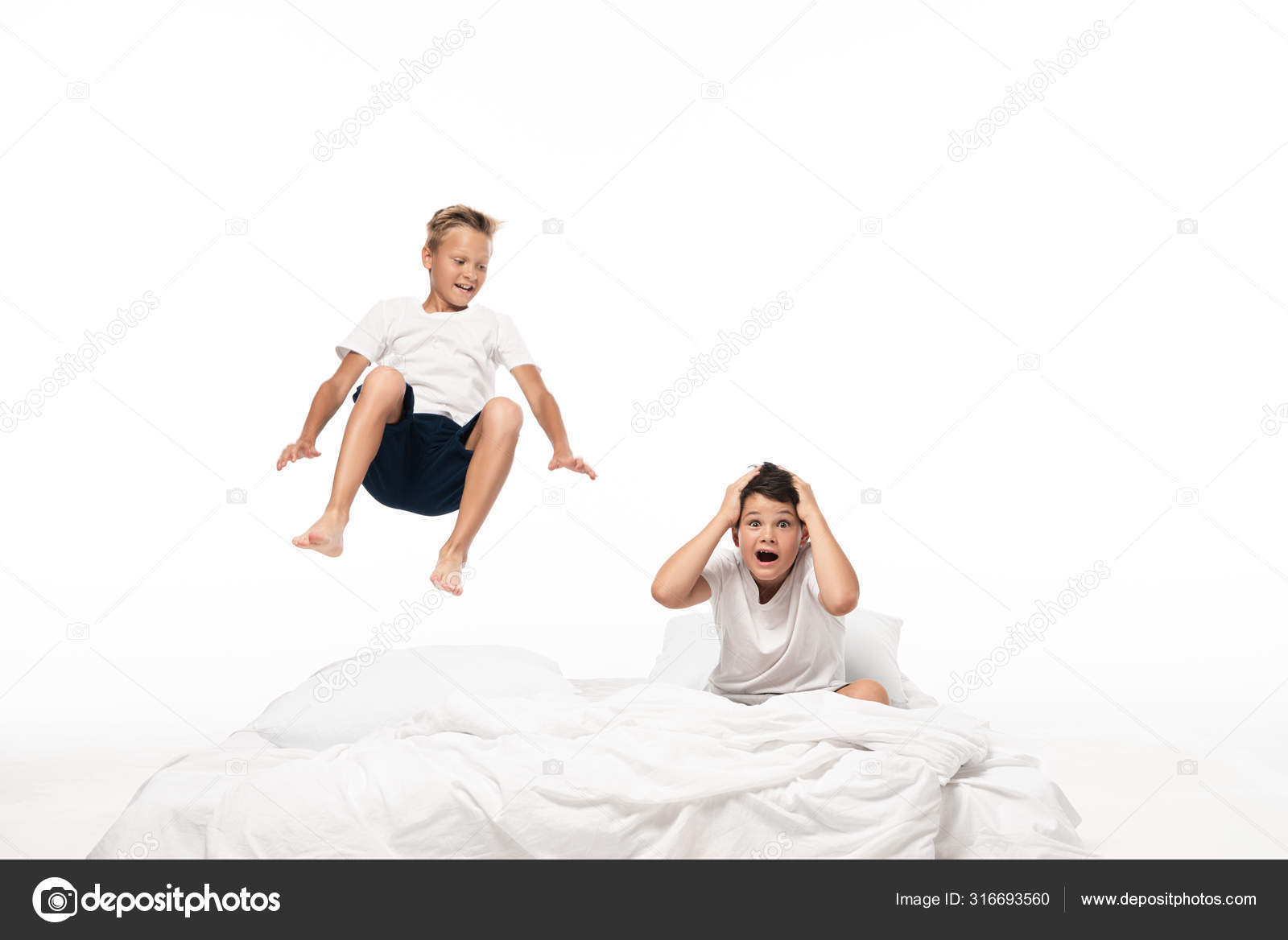 Cheerful Boy Levitating Shocked Brother Sitting Bedding Holding Hands ...