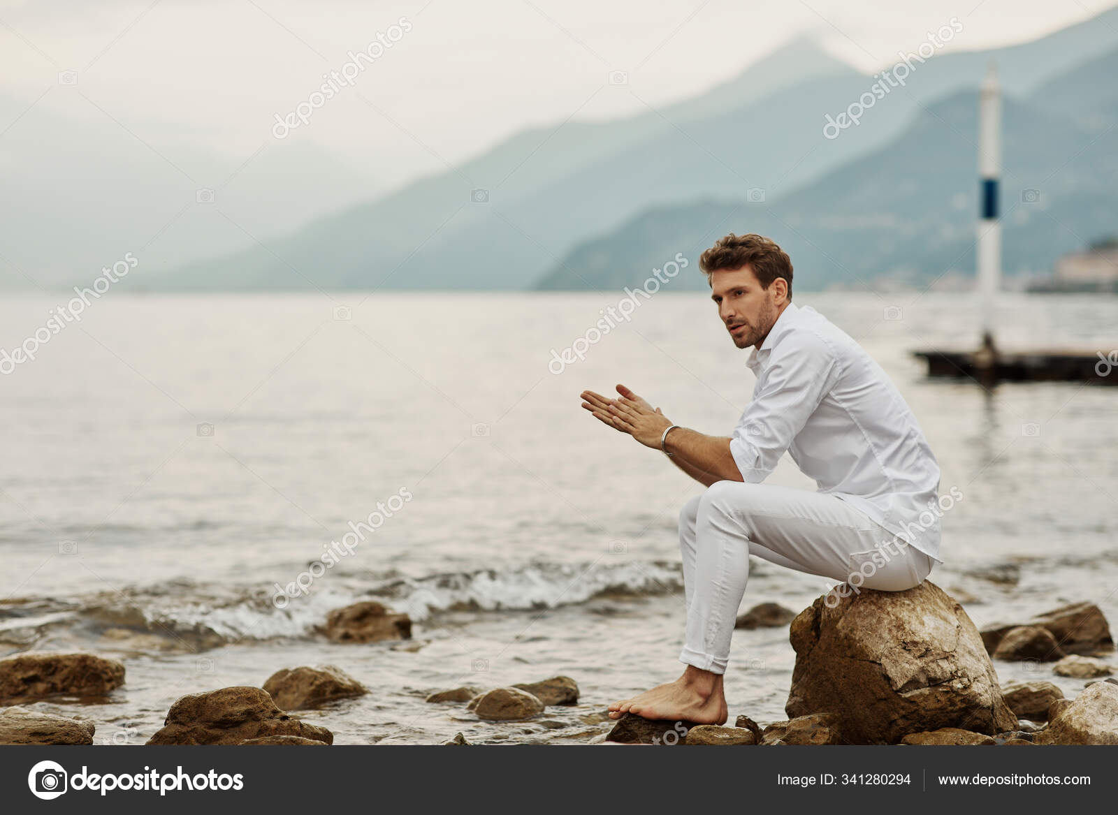 Handsome male model sits on a background of lake and mountains Stock ...