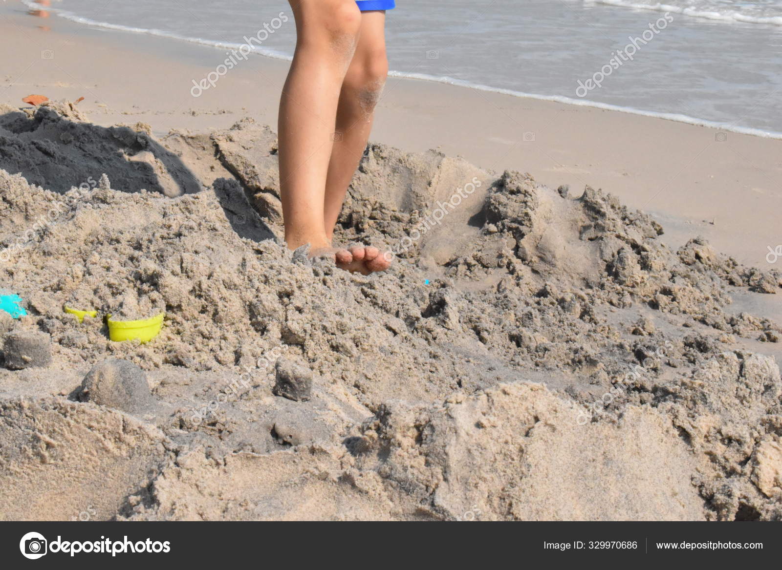 Trampling feet sand. Little boy breaks a sand castle. The child treads ...