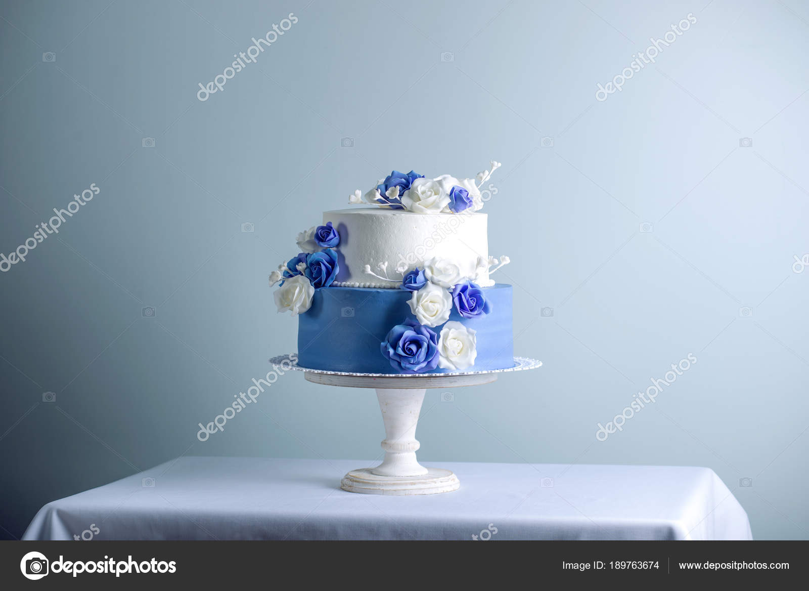 Hermoso pastel de boda de dos niveles blanco y azul decorado con flores ...