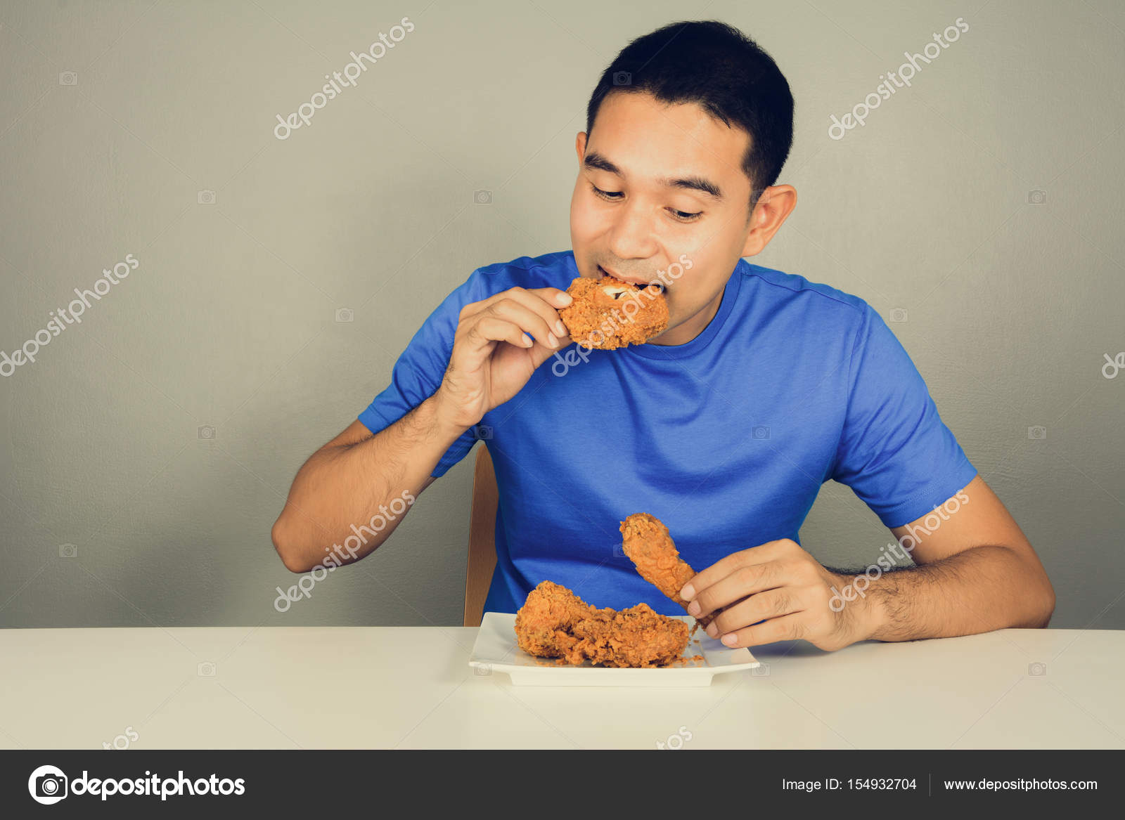 Young man eating fried chicken on the table Stock Photo by ©kritchanut ...
