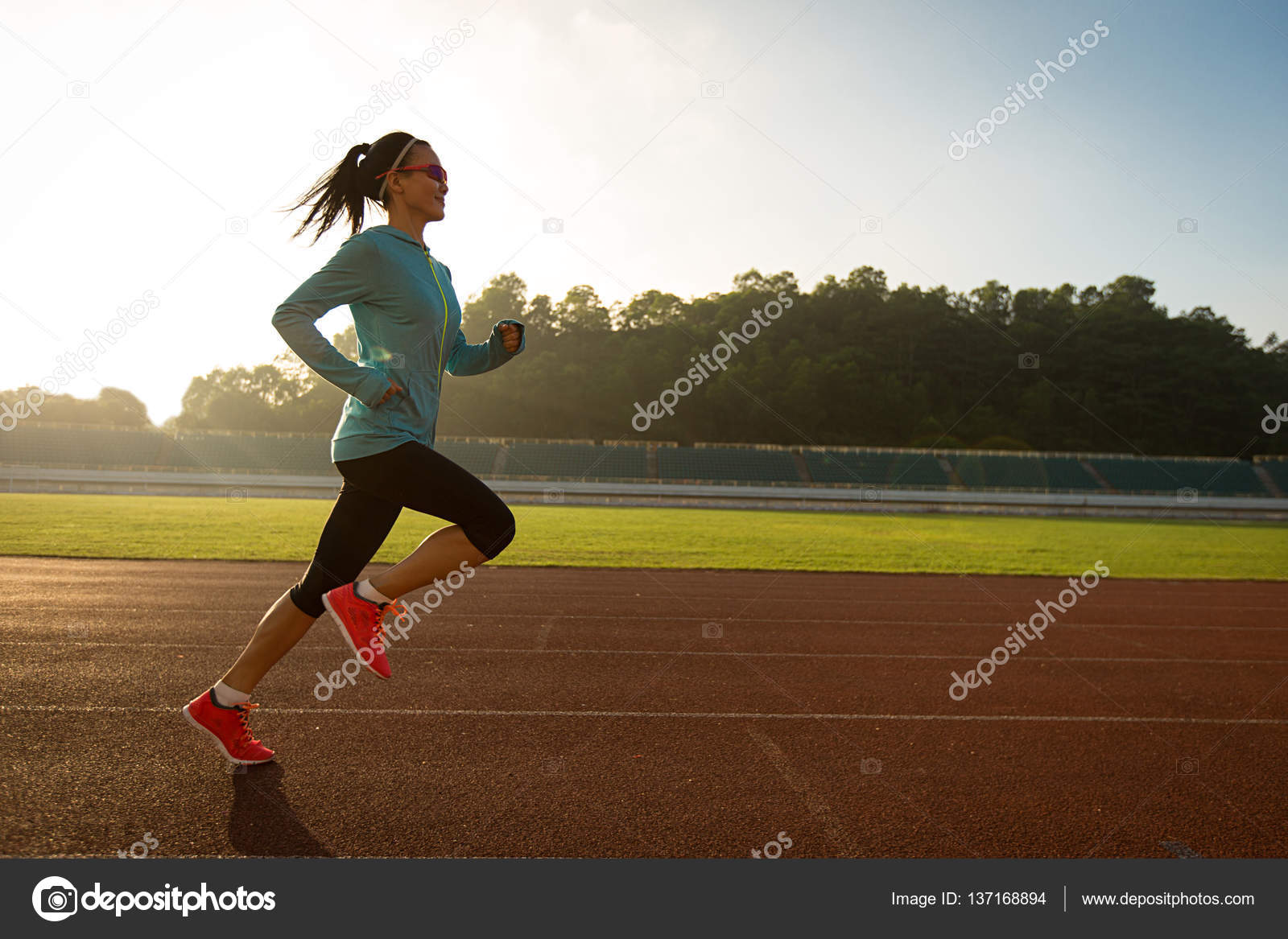 Young woman running on stadium Stock Photo by ©lzf 137168894
