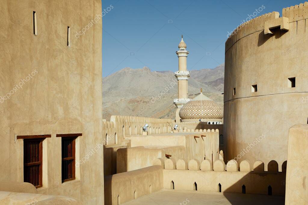 Vista entre torres de vigilancia de fortaleza histórica a mezquita. Nizwa, Sultanato de Omán. 2023