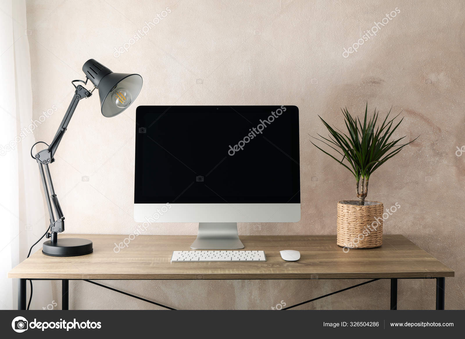 Workplace with computer and plant on wooden table. Light brown b Stock ...