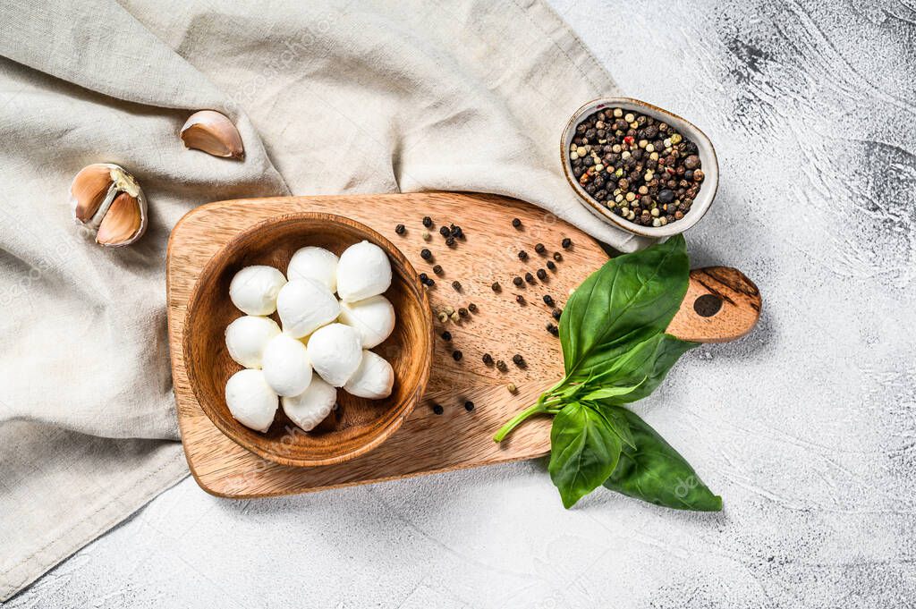 Mini queso mozzarella en un tazón de madera con hojas de albahaca ...