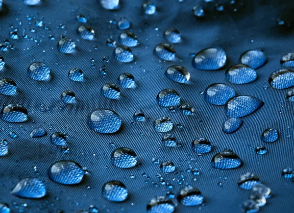 Rain water droplets on blue fiber waterproof fabric. Blue background ...