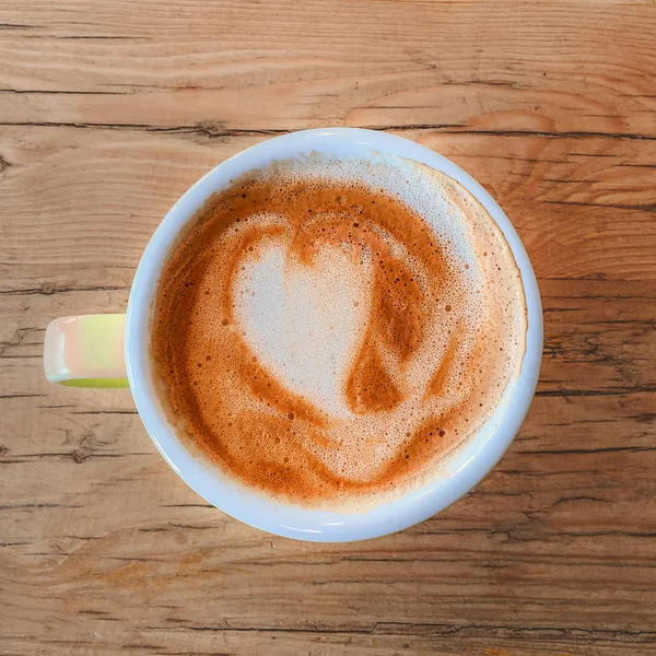 Cup of coffee with heart pattern in colorful cup on rustic wooden table ...