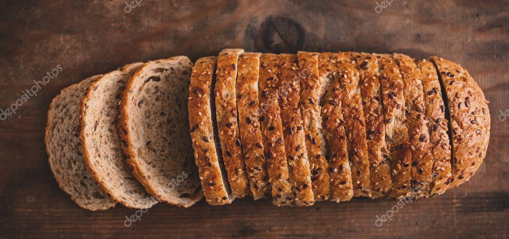 pan integral en rodajas sobre fondo rústico oscuro de madera 2022