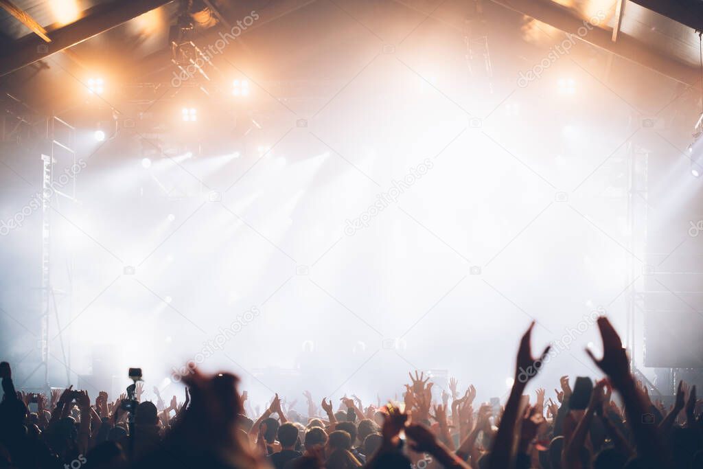 Luces de escenario y multitud de espectadores con las manos levantadas ...