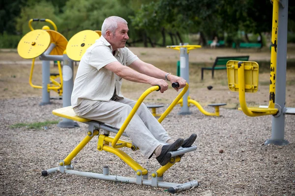 Old man making exercises on outdoor gym. - Stock Image - Everypixel