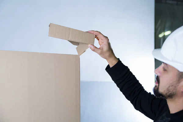 Man with a hard hat assembling carton box in a warehouse. Cardboard ...