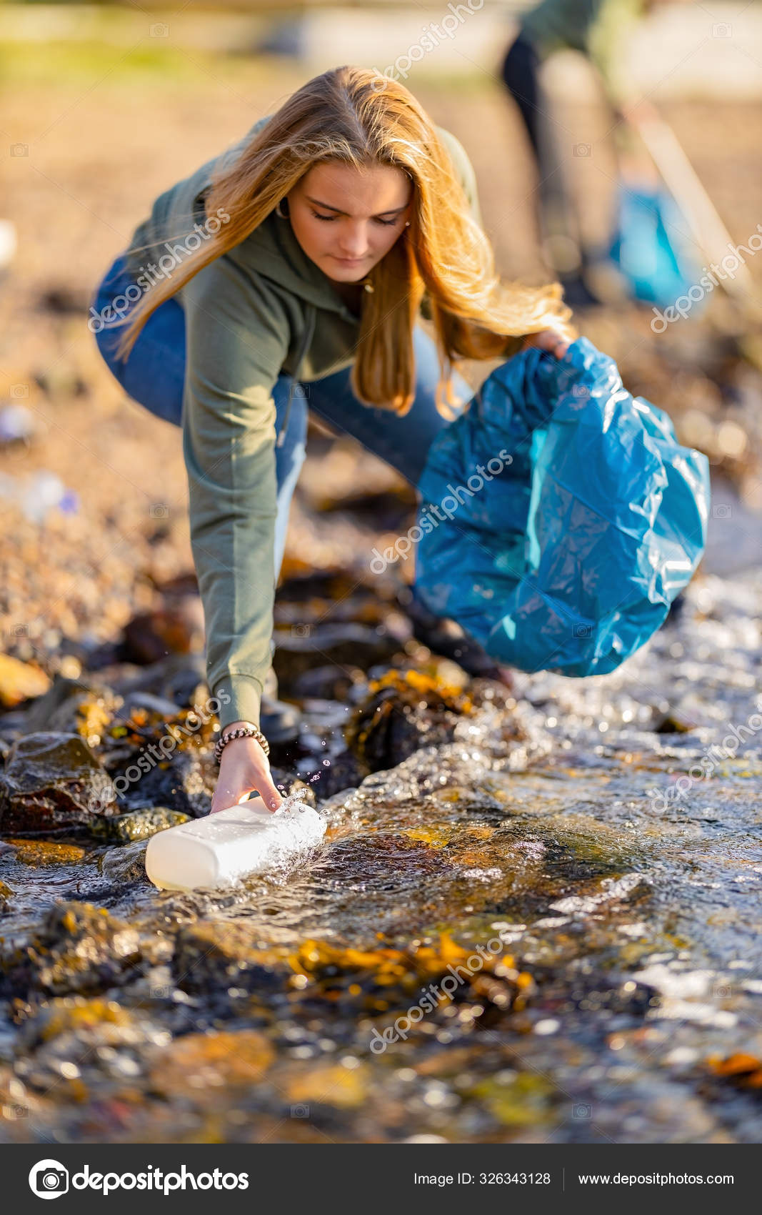 Young woman picking up garbage from rocky shore — Stock Photo © kjekol ...