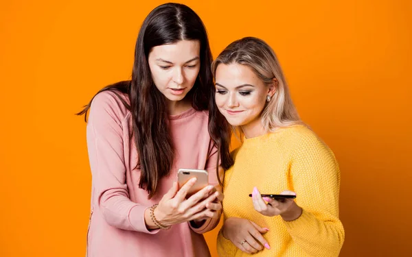 Two cheerful friends communicate and show each other something in ...