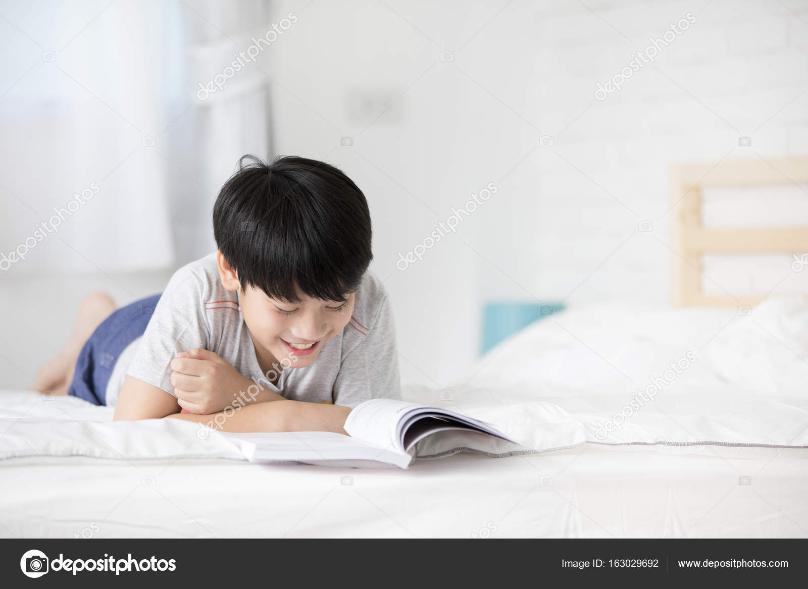 Asian boy rest on the bed and reading book — Stock Photo © sirikornt ...