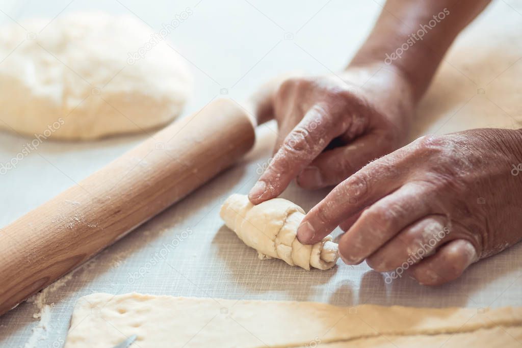 Manos femeninas rodando masa en rollos. Proceso de fabricación de ...