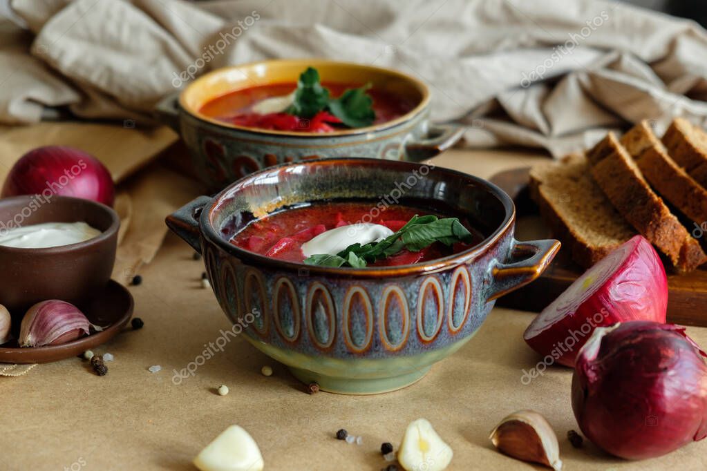 Sopa borscht sobre fondo beige en un plato de barro con ajo, cebolla ...