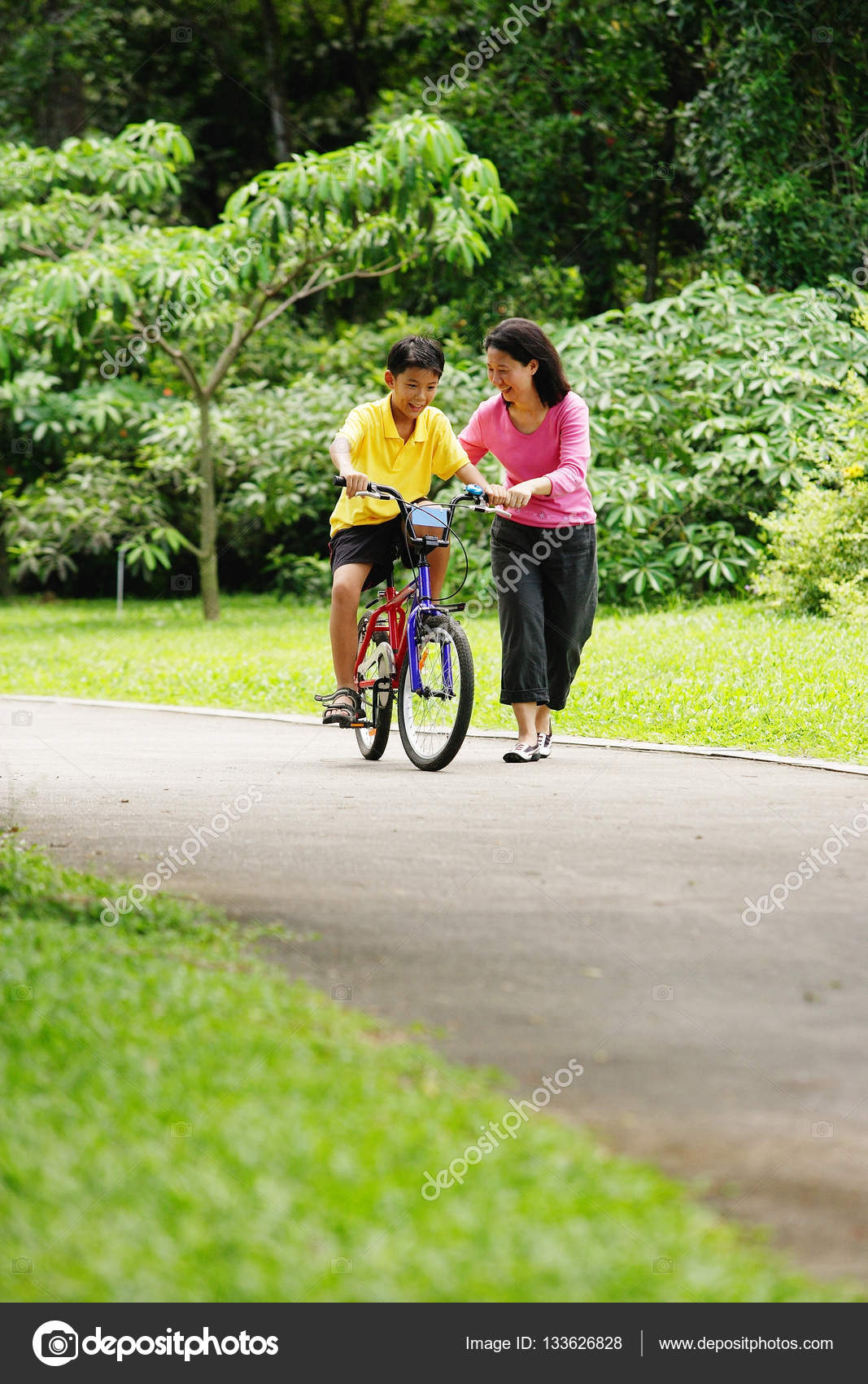 Mother guiding son on bicycle Stock Photo by ©MicrostockAsia 133626828