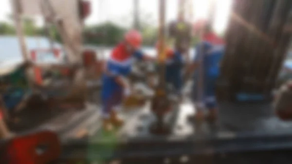 Blurry view of Oil workers check oil pump. Roustabouts doing dirty and ...