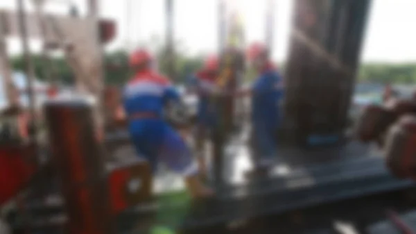 Blurry view of Oil workers check oil pump. Roustabouts doing dirty and ...
