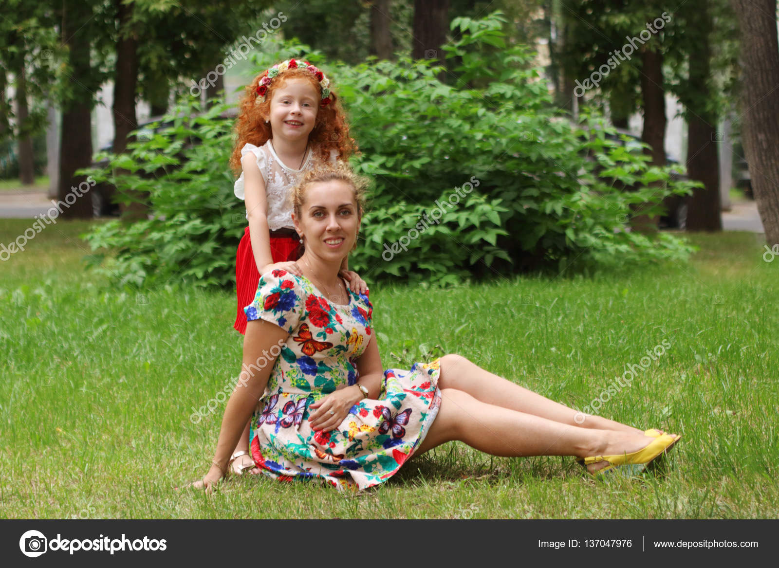 Little girl poses with her mother on lawn in summer park, shallo Stock ...