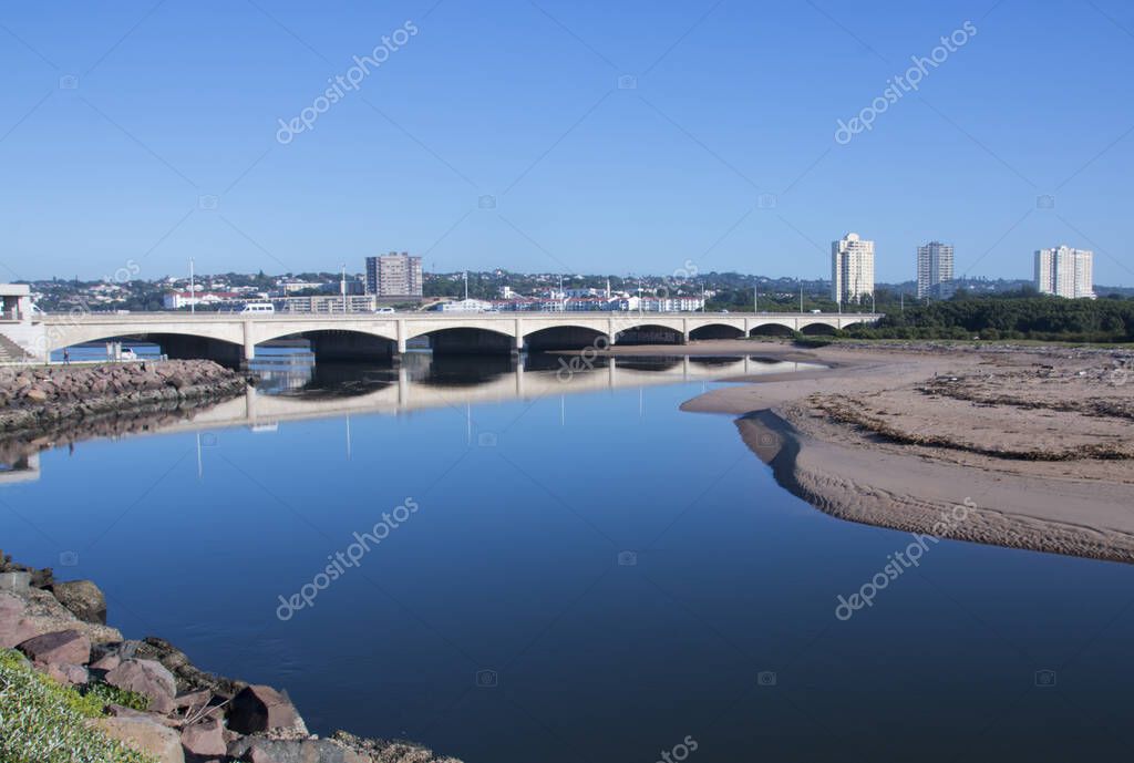 Reflexión del puente sobre la laguna azul en la desembocadura del río ...