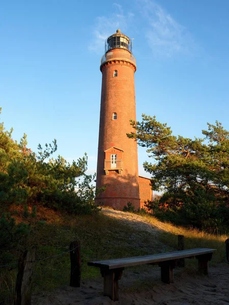 Shinning old lighthouse above houses before sunset. Tower illuminated ...