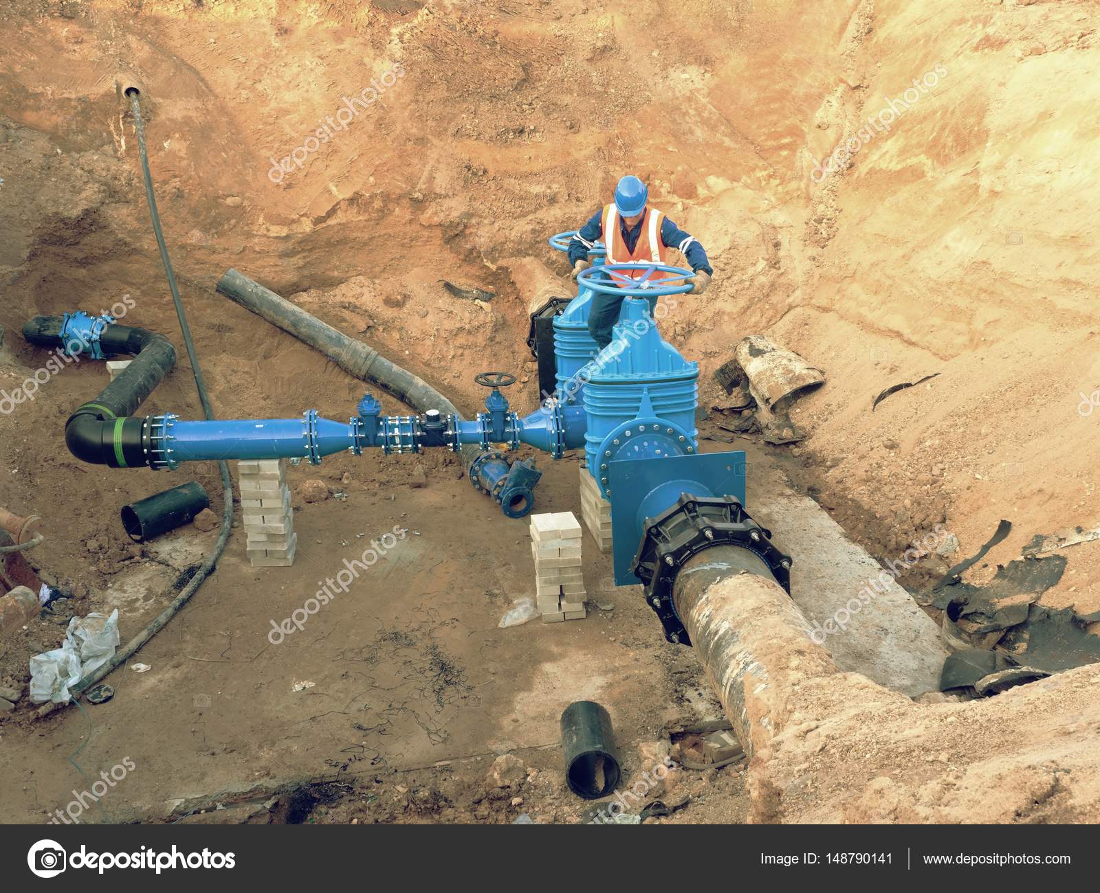Worker in safety clothes drive valve conduit on City potable water pipe ...