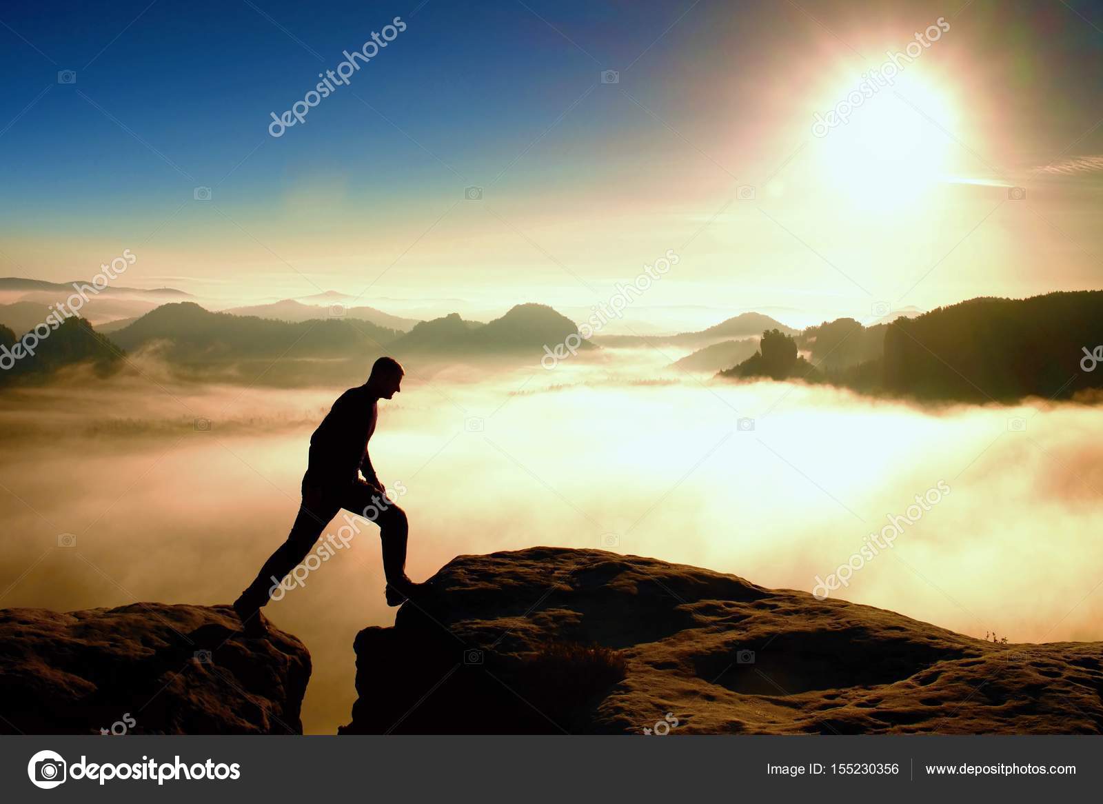 Crazy hiker in black is jumping between the rocky peaks. Wonderful ...
