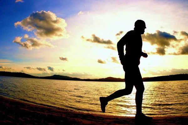 Training at sunset.Running tall man. A silhouette of jogger at path ...