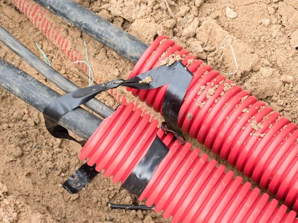 Excavation of trench with black cables in protective HDPE tube. Lines ...