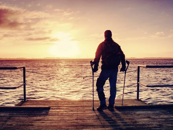 Hurt man with hooded jacket and forearm crutches looking sadly - Stock ...