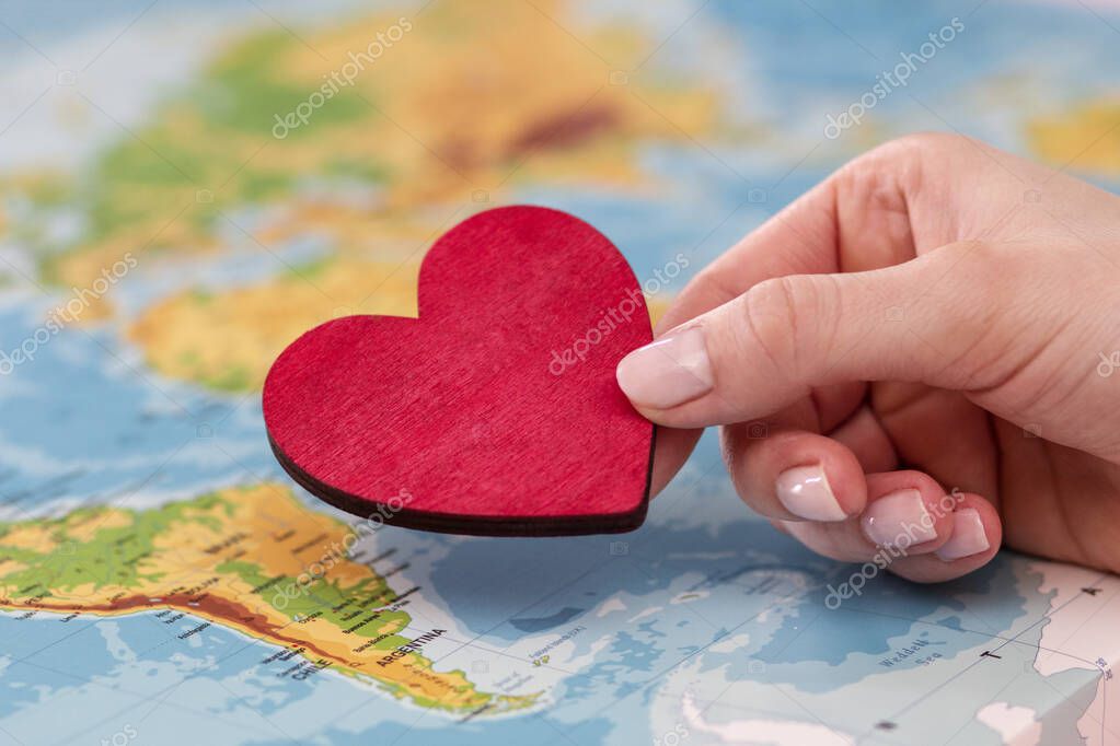 hombre sostiene el corazón rojo en el fondo del mapa del mundo 2022