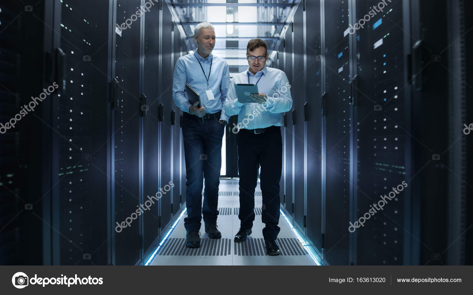 In Data Center Two IT Engineers Walking Through Rows of Server R ...