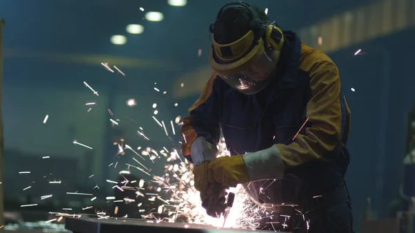 Heavy industry worker at a factory is working with metal on a an ...