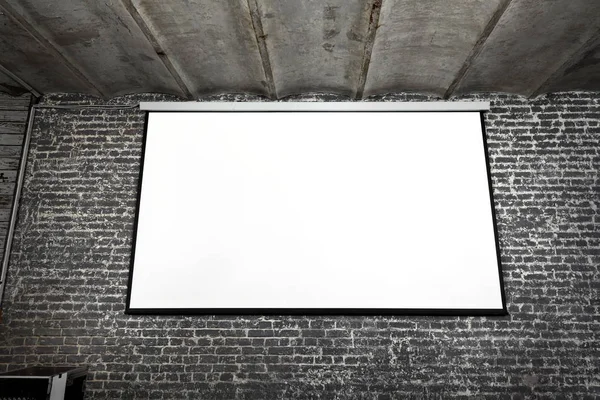 Image of white projector screen on grey brick wal - Stock Image ...