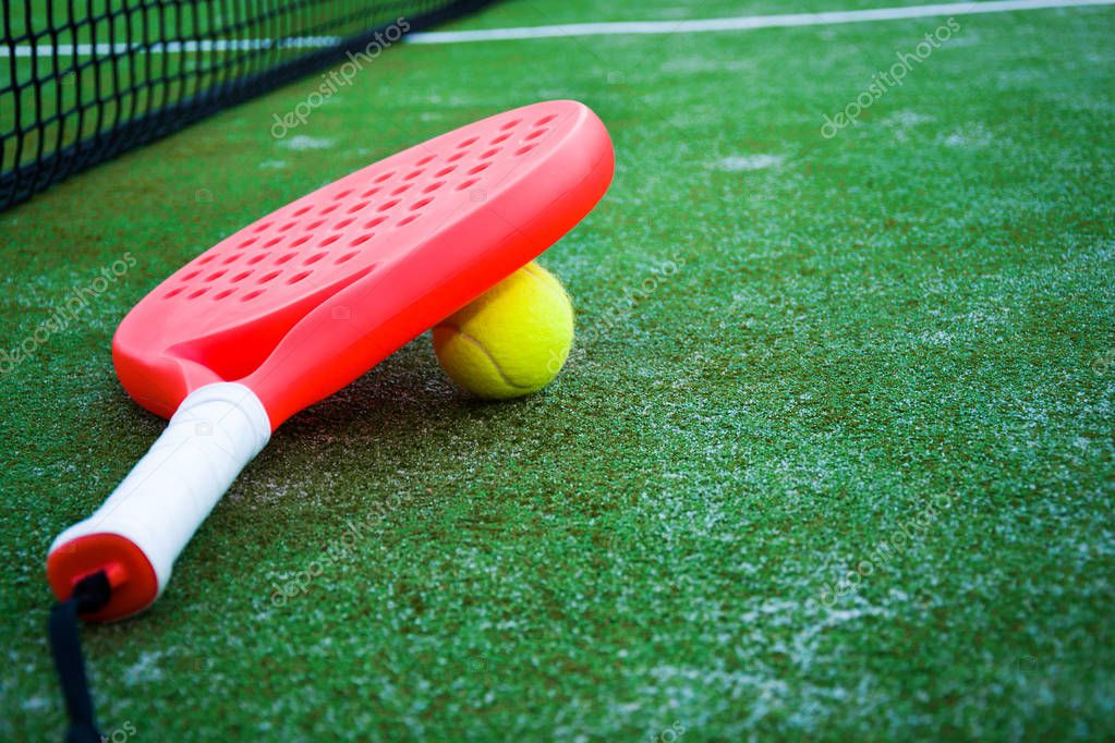 Paddle raqueta de tenis, pelota y red en el césped. Espacio de copia 2023