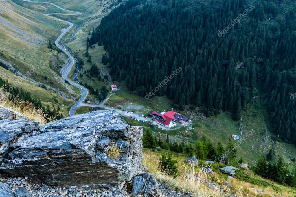 Primer plano de una roca de montaña con chalet de montaña y gran bosque ...